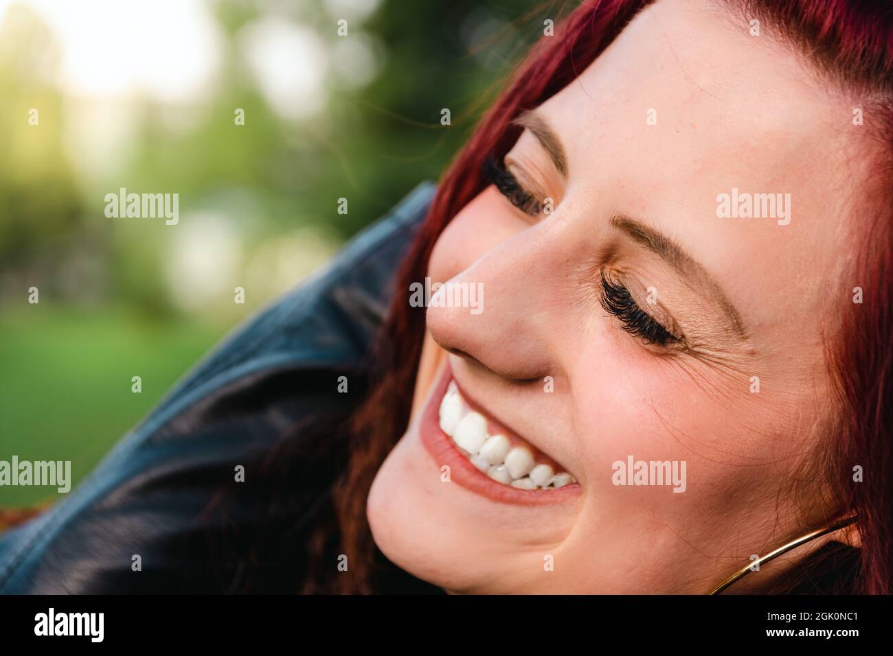 A closeup shot of a Caucasian woman with red hair, laughing happily in ...