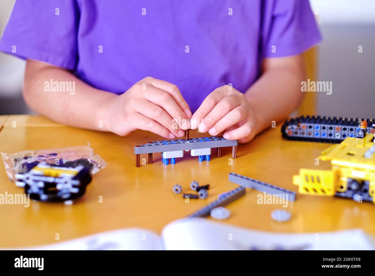 Close up of boy hands building plastic brick blocks on table at home ...