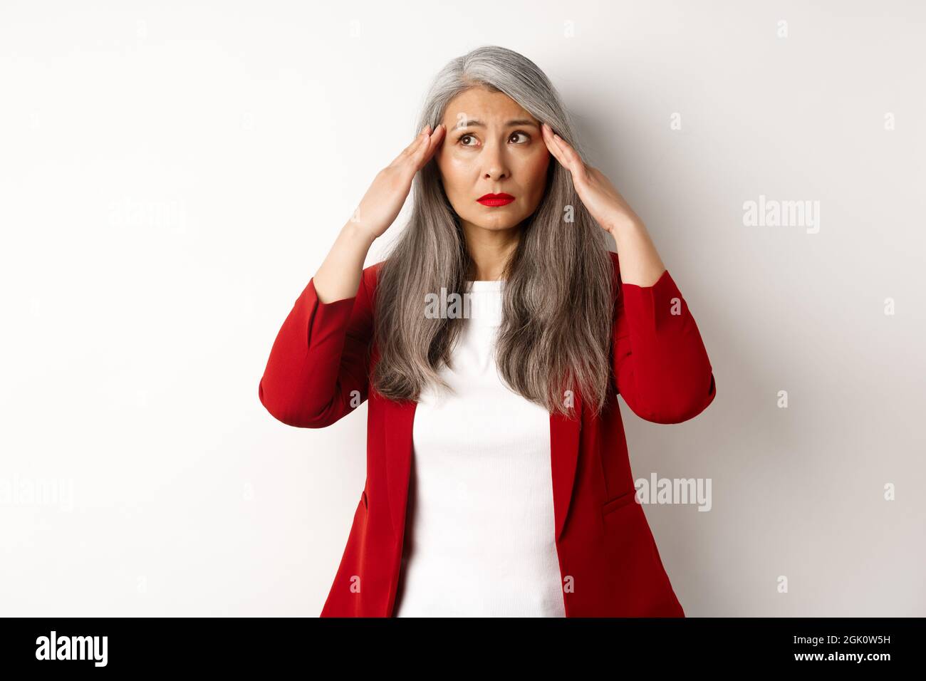 Troubled asian office woman touching head, looking aside and looking ...