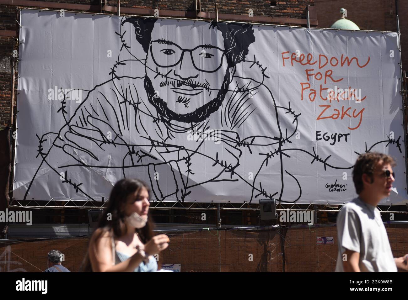 People walk by a banner demanding the freedom of journalist Patrick ...