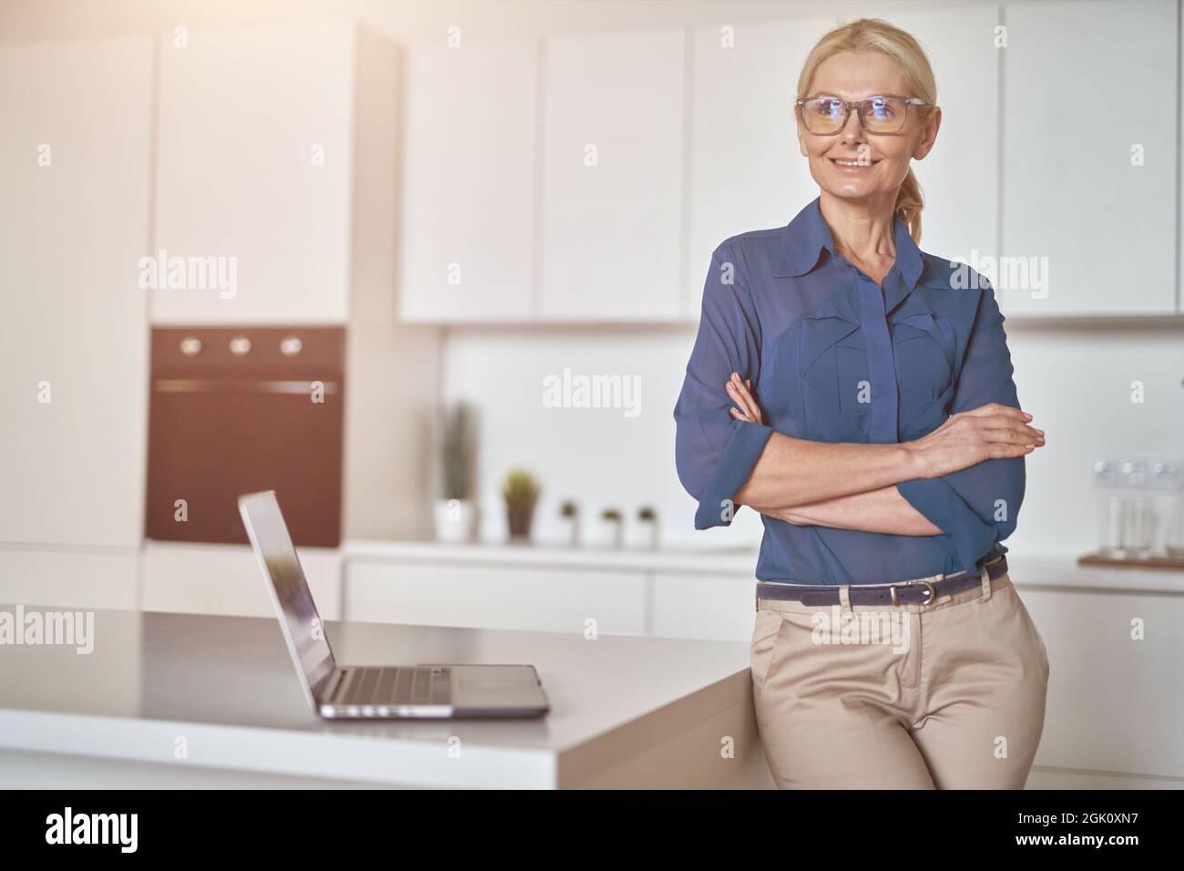 Confident mature businesswoman in glasses smiling aside, working at ...
