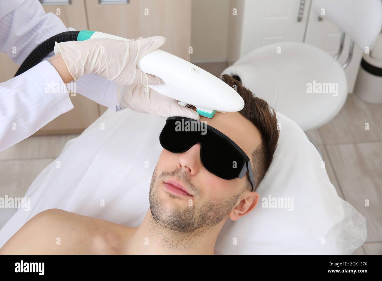 Handsome man getting laser epilation in beauty salon Stock Photo - Alamy