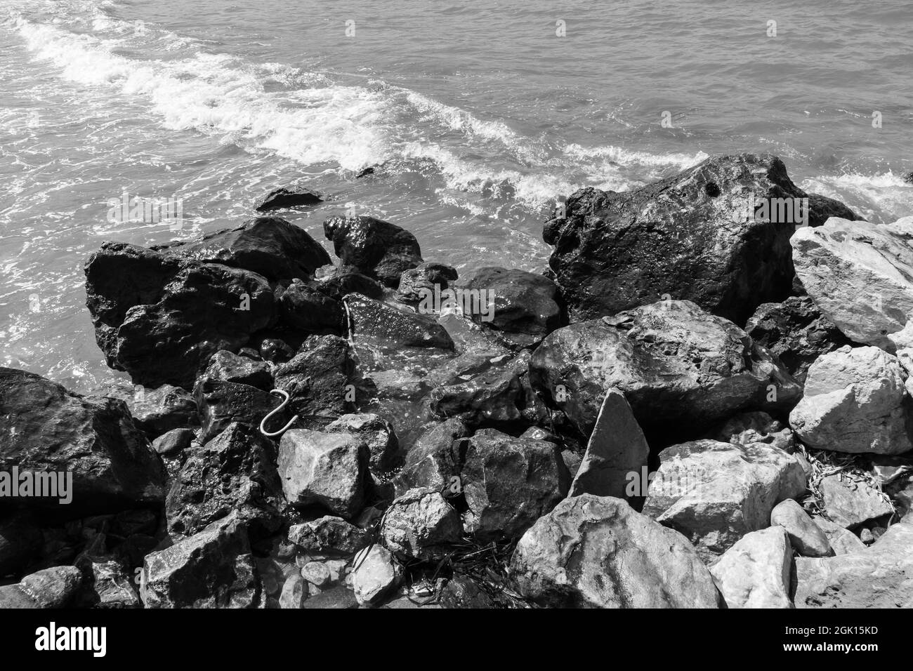A grayscale shot of large rocks at the beach Stock Photo - Alamy