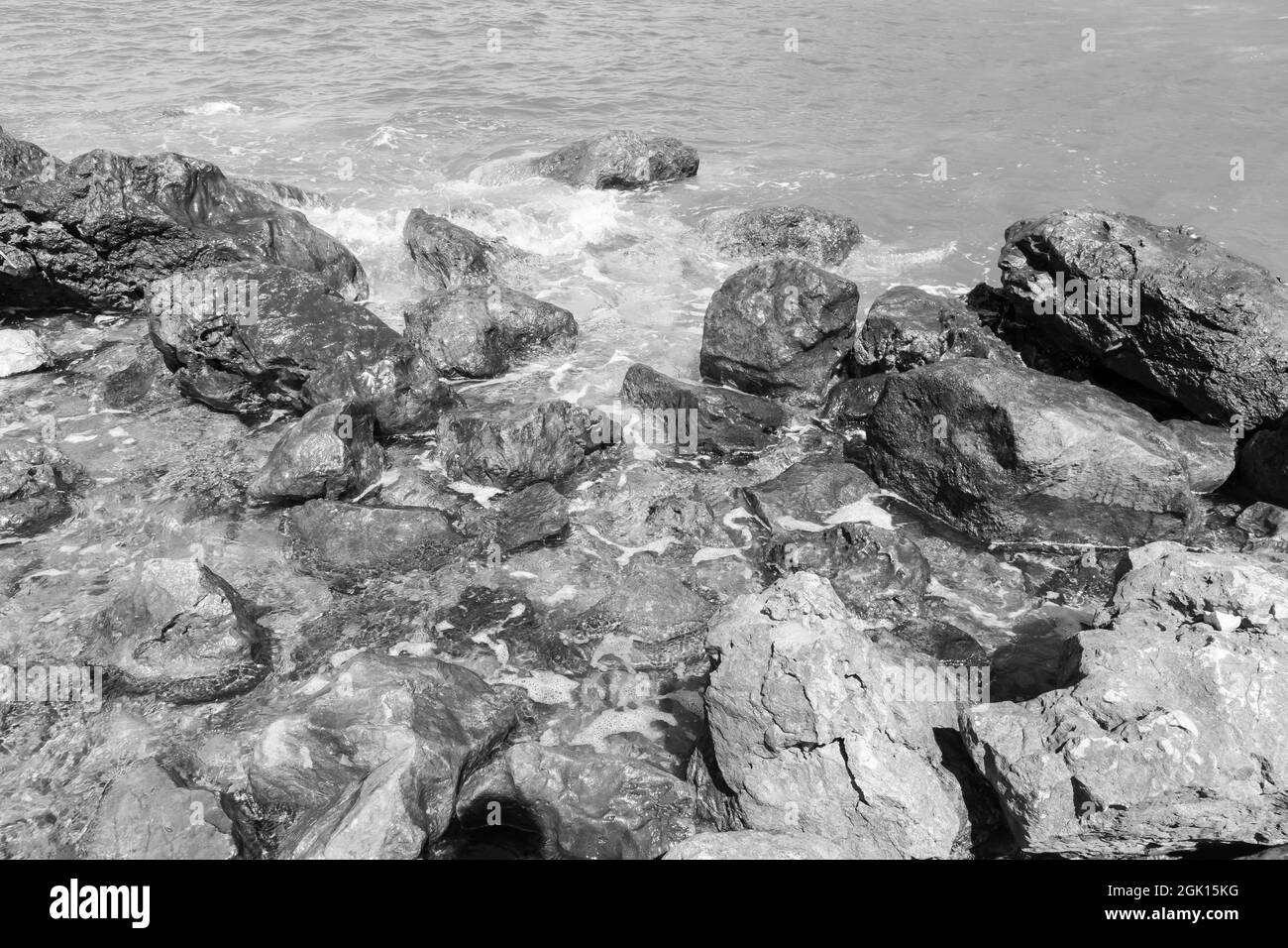 A grayscale shot of large rocks at the beach Stock Photo - Alamy