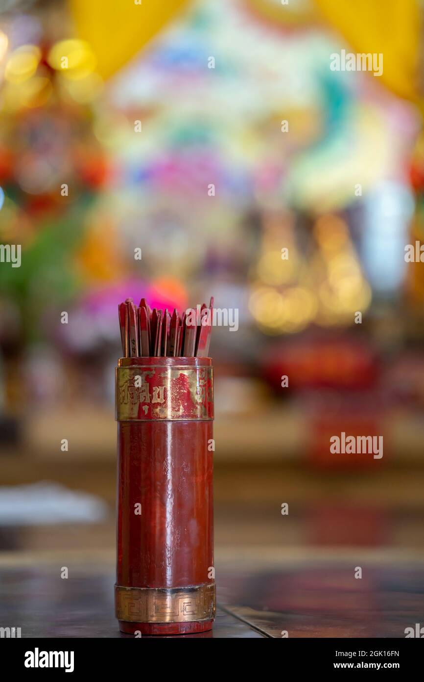 A vertical shot of wooden ritual sticks in a container in a temple with ...