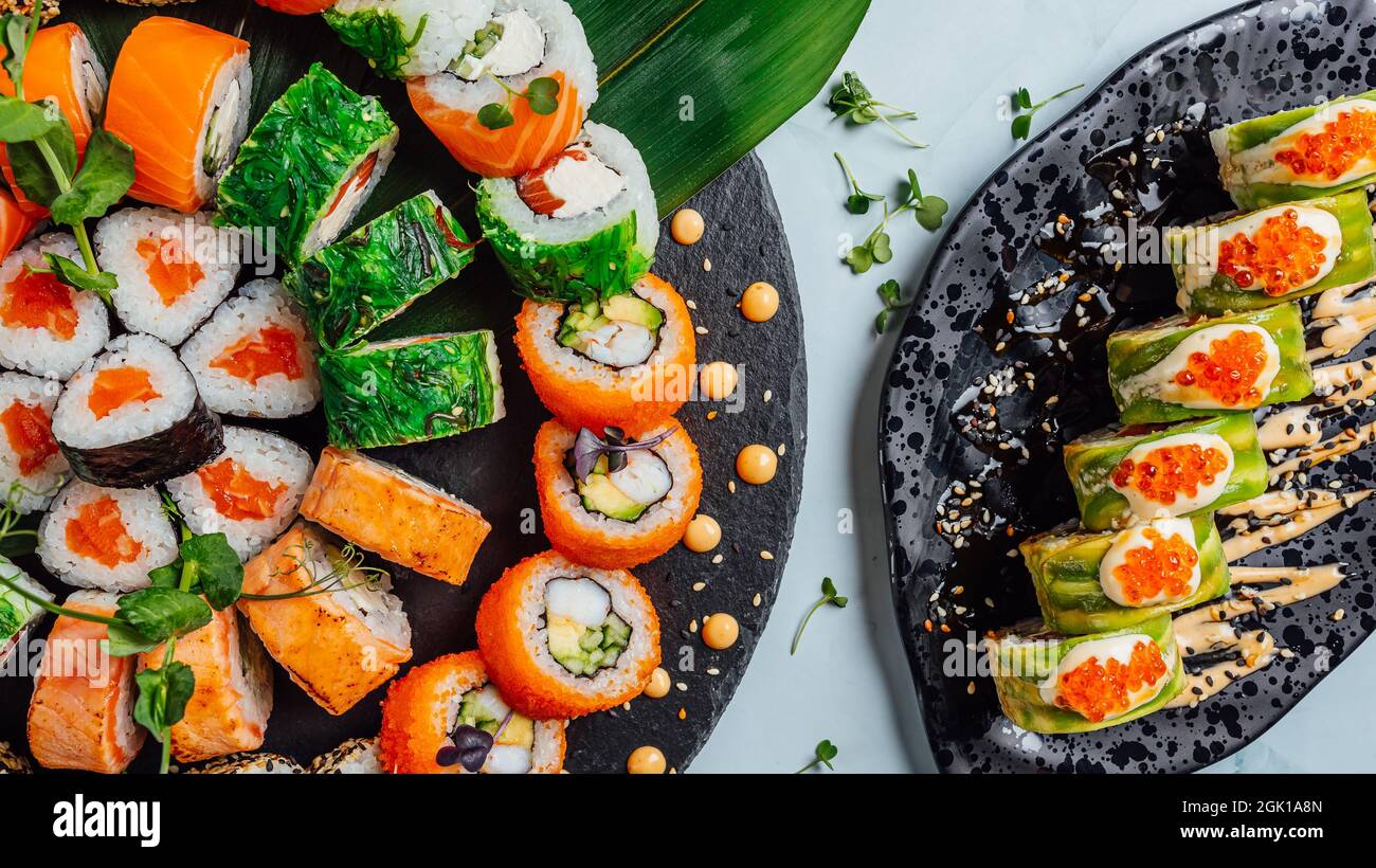 A top view of couple of plates of colorful sushi rolls arranged like ...