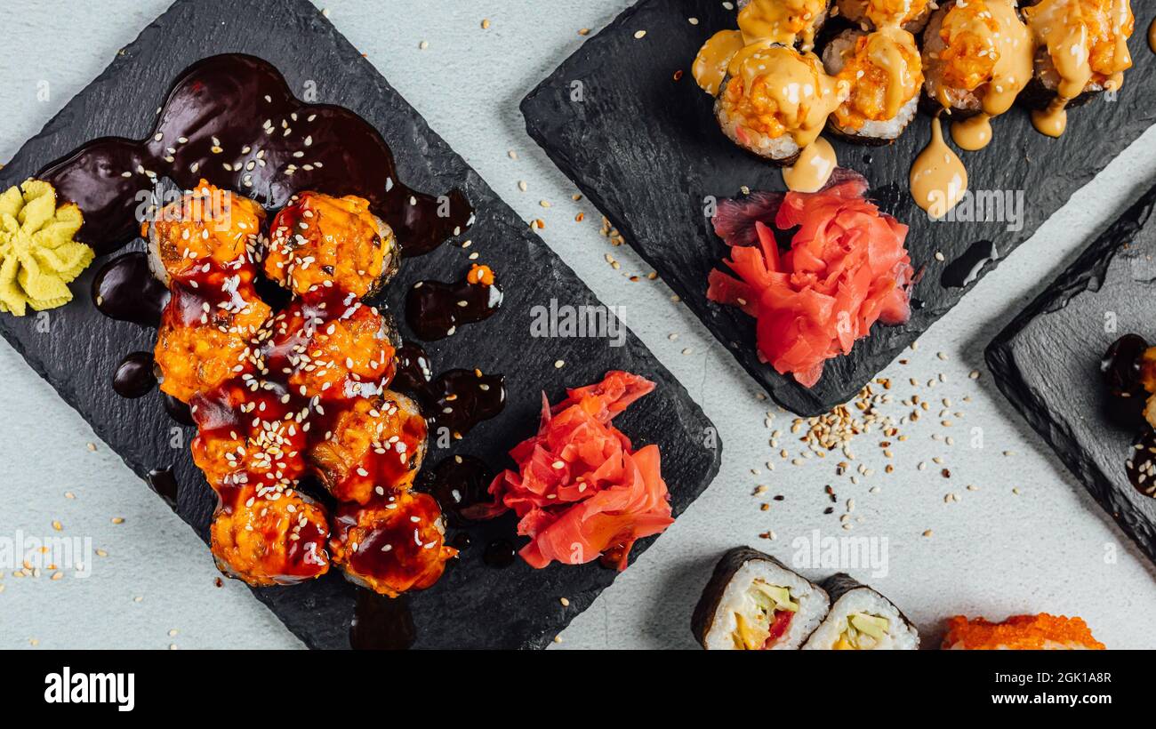A top view of several plates of colorful sushi rolls arranged like ...