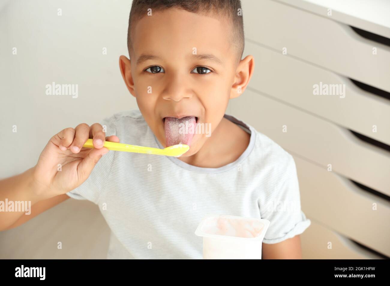 Cute African American boy eating yogurt at home Stock Photo - Alamy