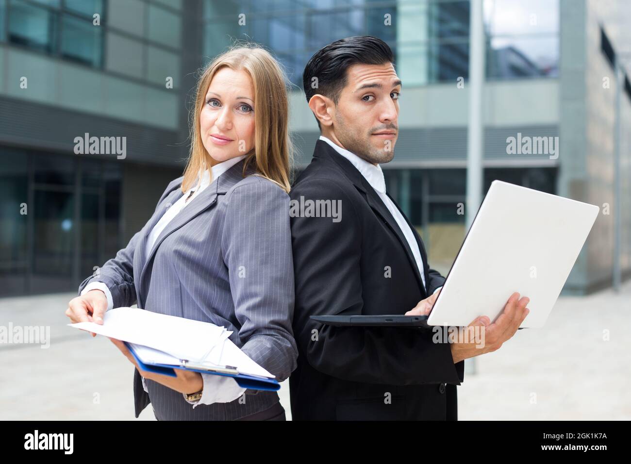 Two office workers are posing with laptop and folder Stock Photo - Alamy