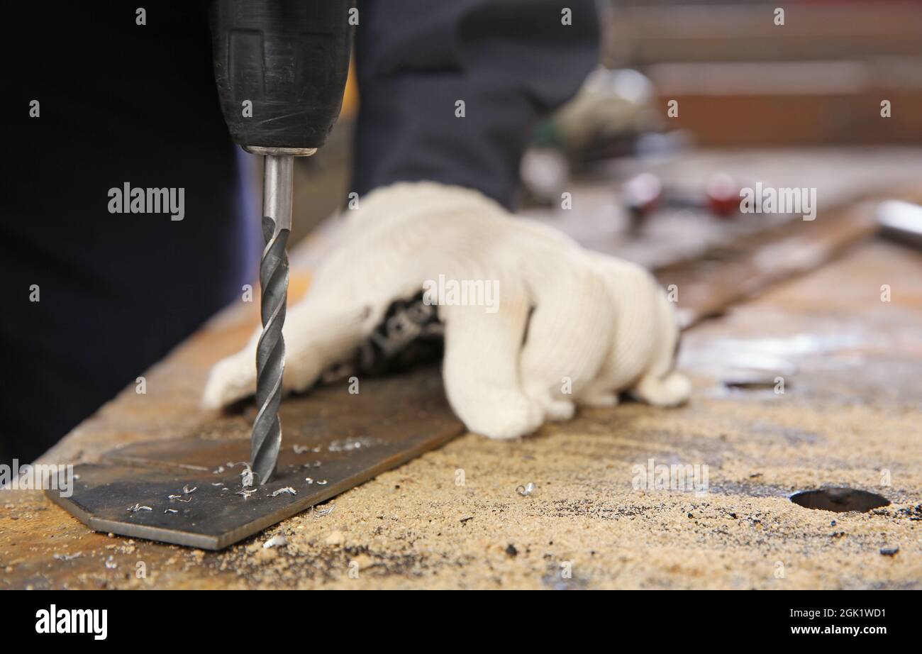 Worker using drill for metalworking at shop Stock Photo - Alamy