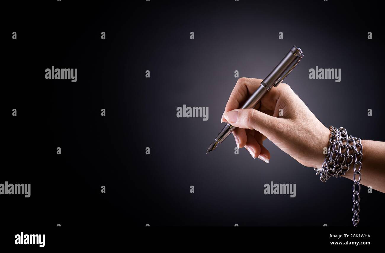 World press freedom day concept. Hand holding a pen with chain on dark ...