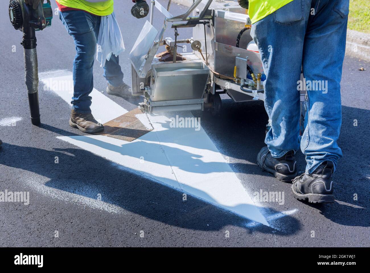 Worker thermoplastic spray marking machine painting work on the street ...