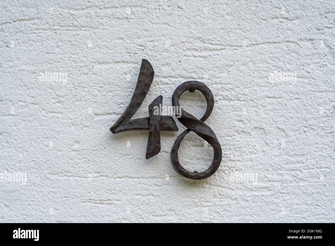 Metal house number 48 on a white stucco wall background, close up Stock ...
