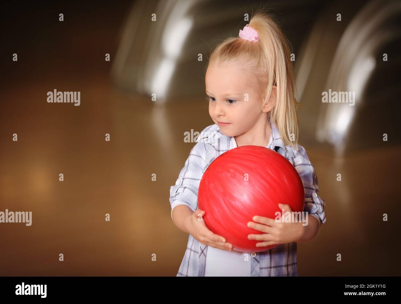 Cute child with ball in bowling club Stock Photo - Alamy