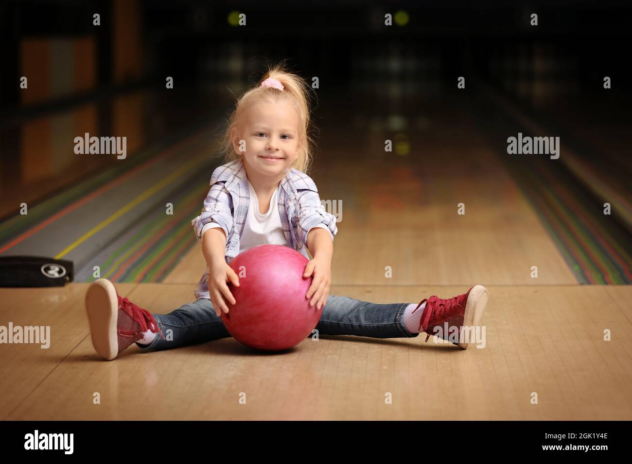 Cute child with ball in bowling club Stock Photo - Alamy