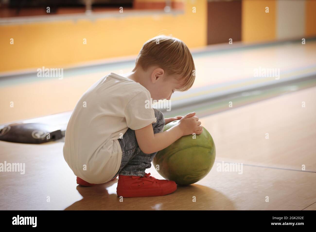 Cute child with ball in bowling club Stock Photo - Alamy