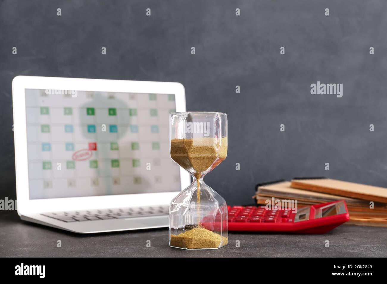 Hourglass and laptop on dark background Stock Photo - Alamy