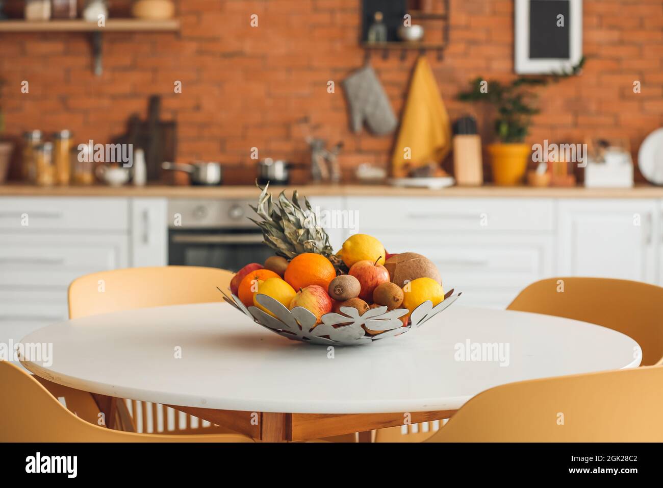 Basket with fresh fruits on dining table in modern kitchen Stock Photo ...