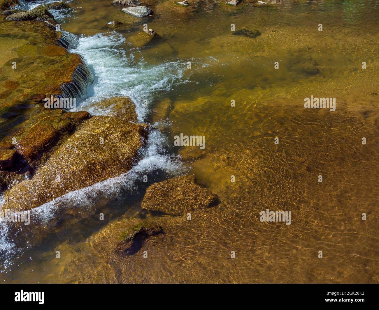 Clear water in a stream, near rocks and waterfalls with copy space ...