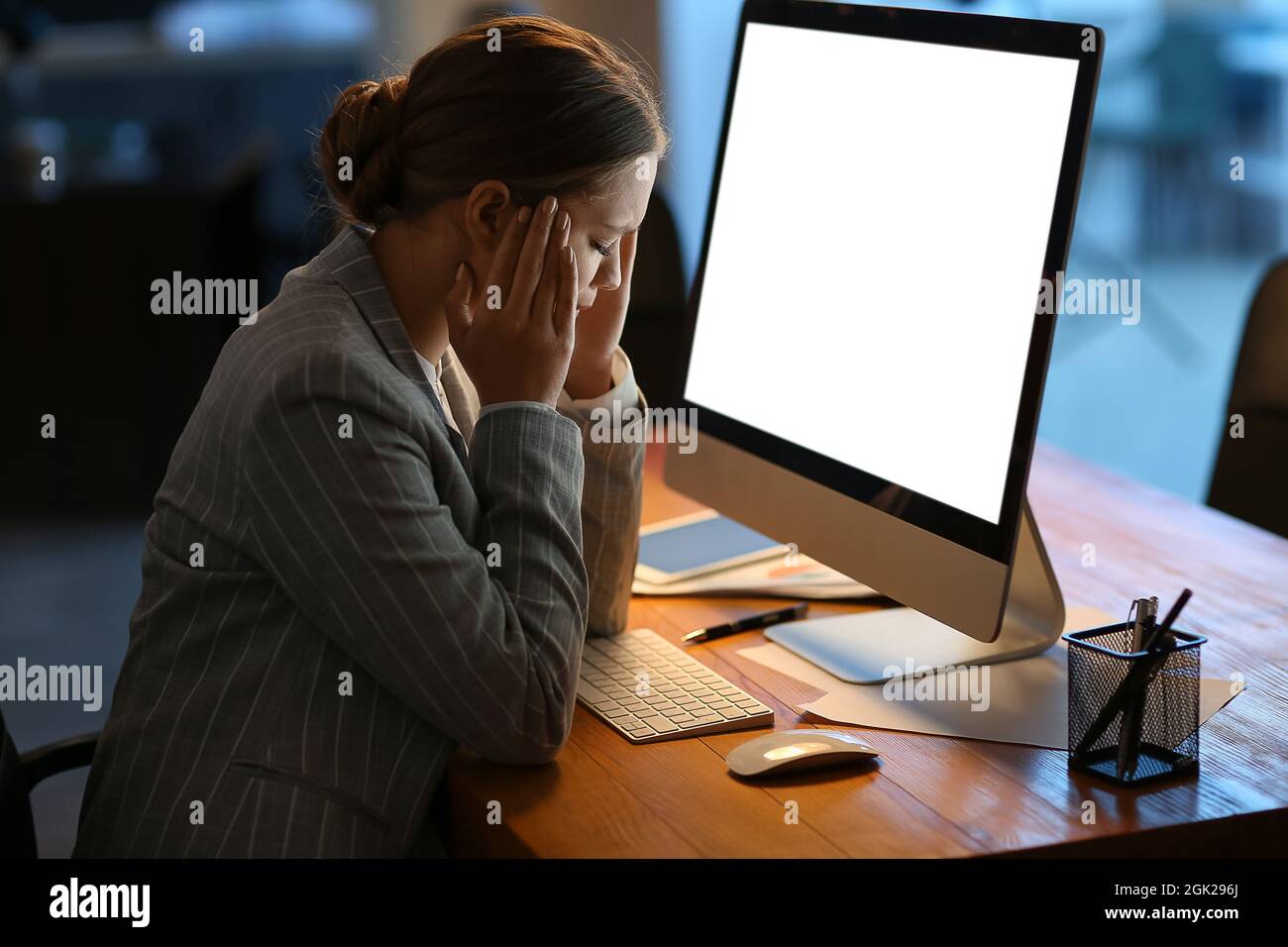 Stressed young woman working on computer in office at night Stock Photo ...