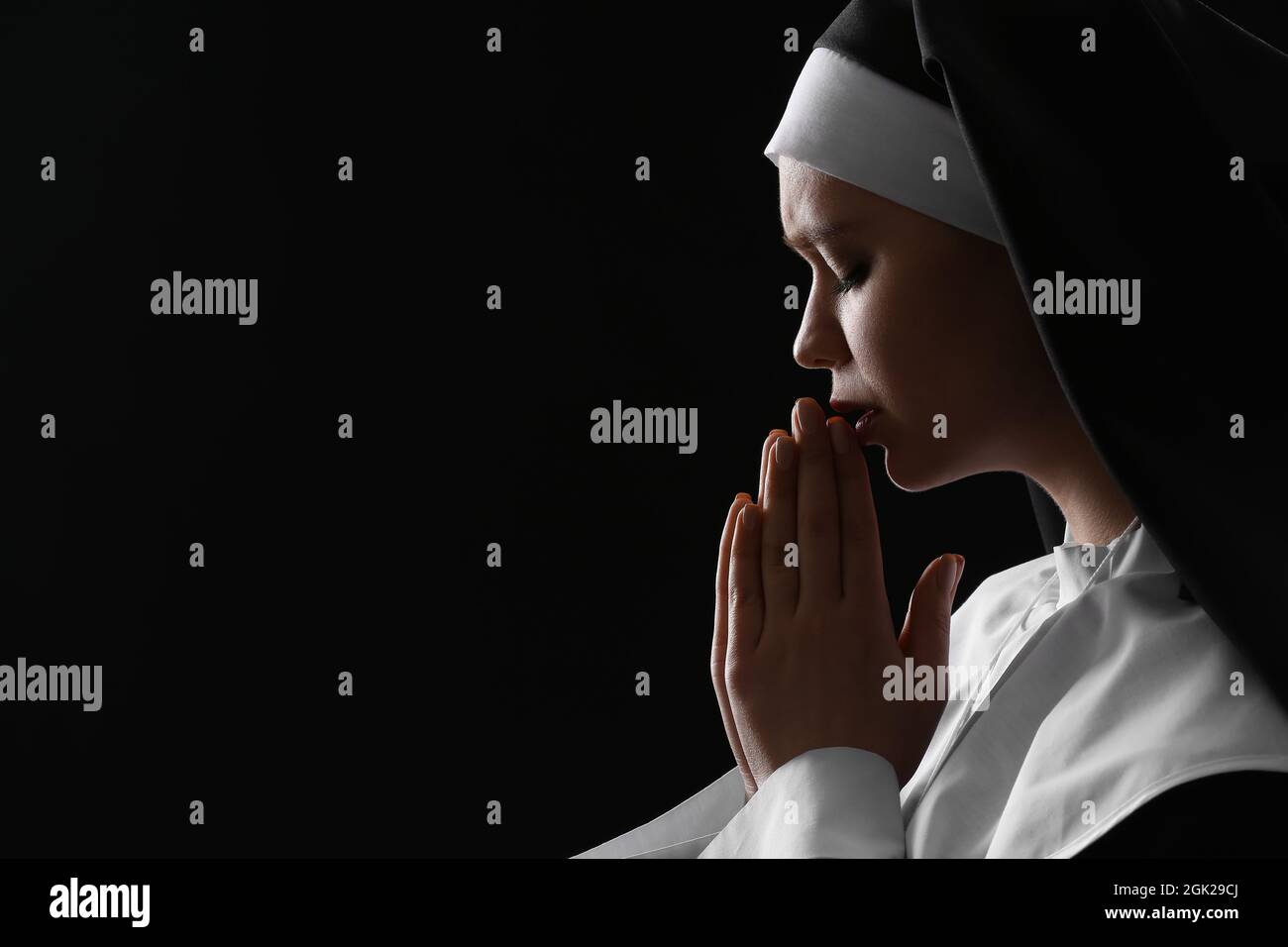 Young praying nun on dark background Stock Photo - Alamy