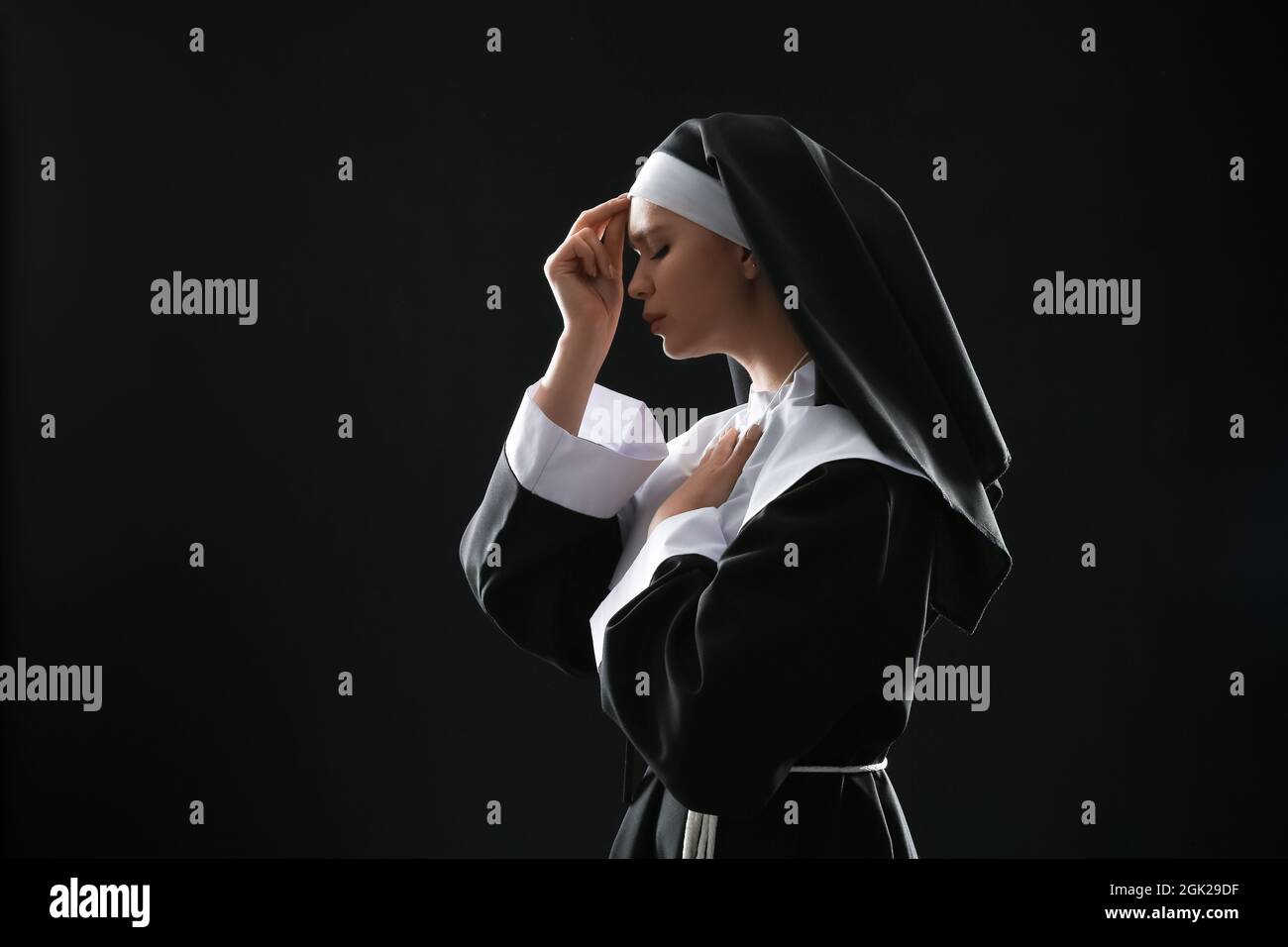 Young praying nun on dark background Stock Photo - Alamy