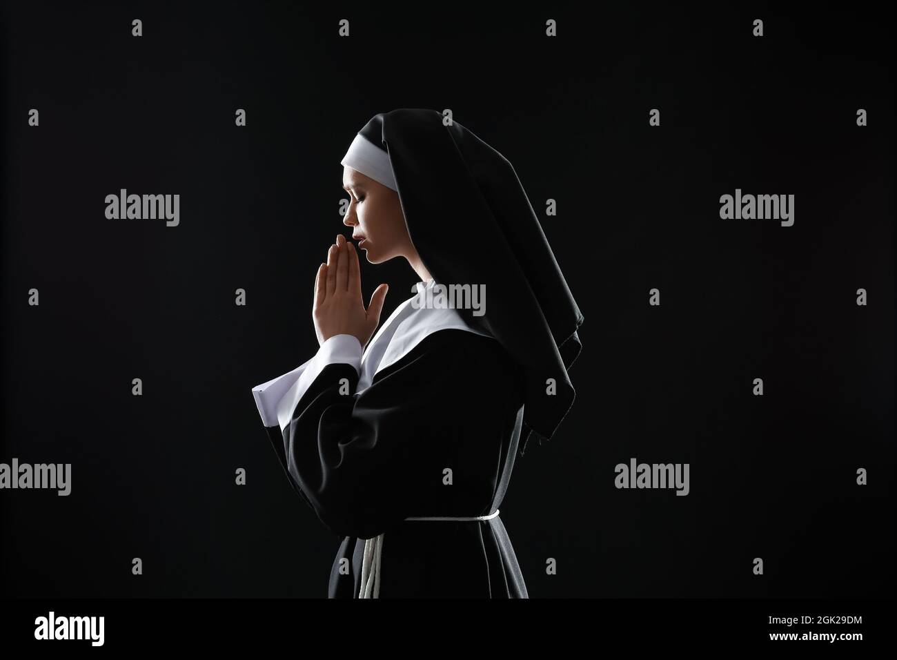 Young praying nun on dark background Stock Photo - Alamy