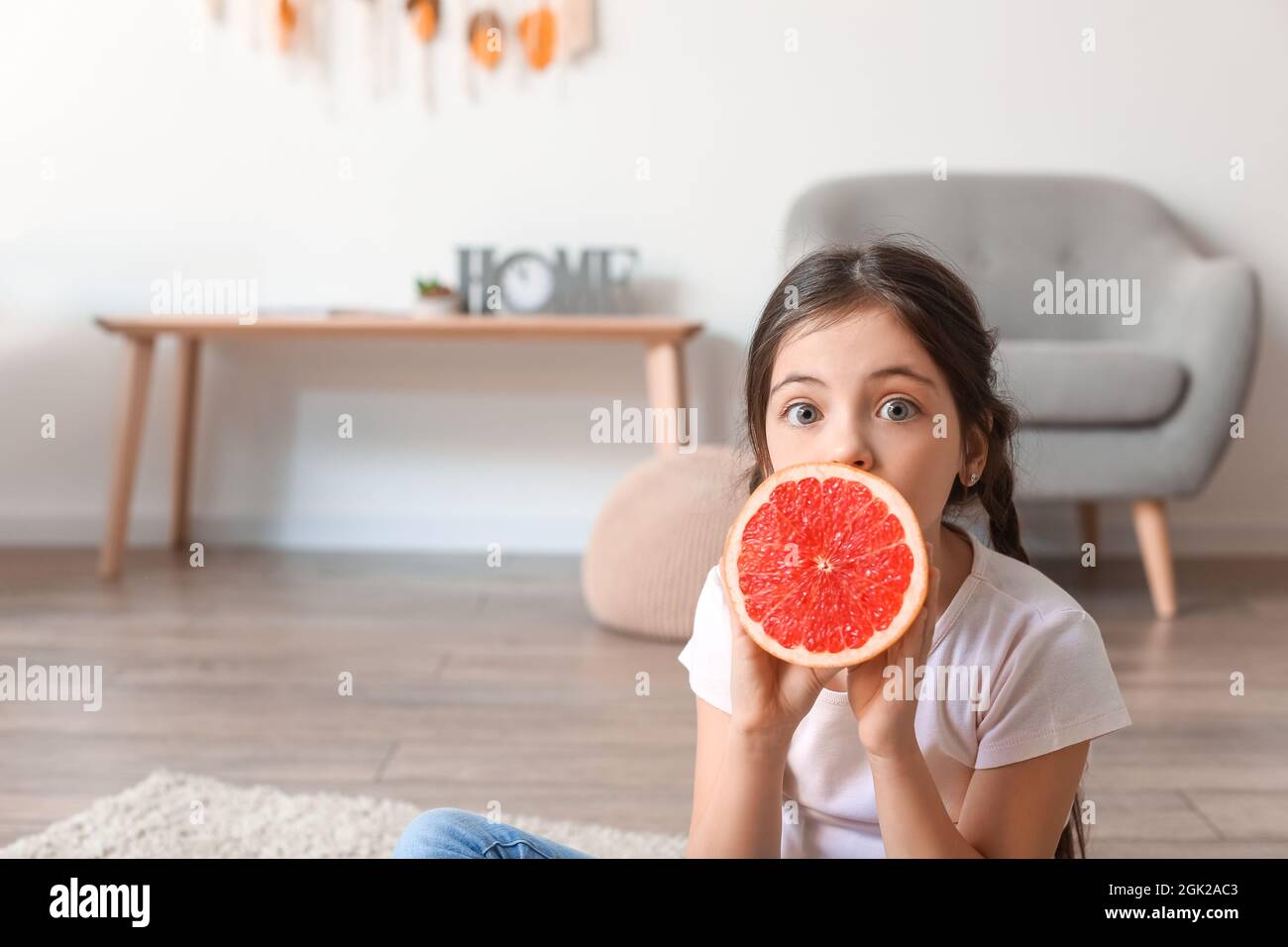 Little girl with fresh tasty grapefruit at home Stock Photo - Alamy