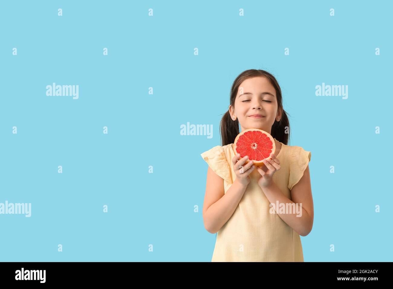 Little girl with fresh tasty grapefruit on color background Stock Photo ...