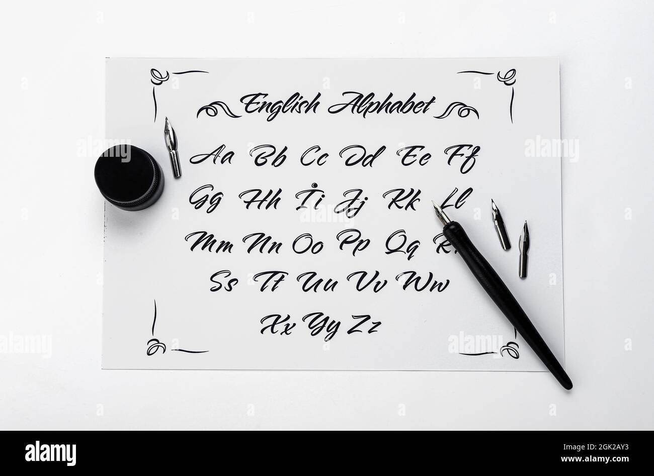 Paper sheet with English alphabet, nib pen and ink on white background ...