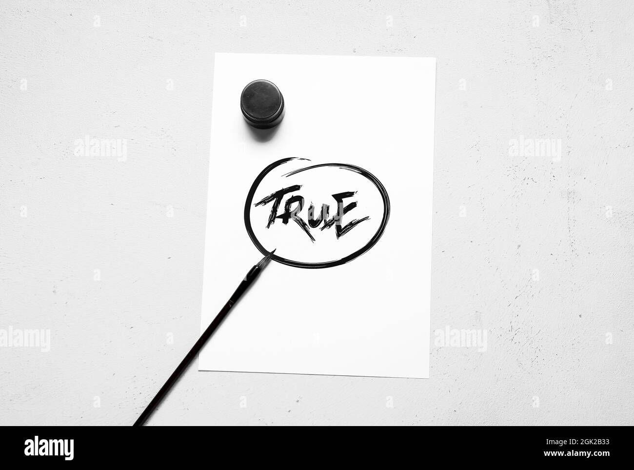 Paper with word TRUE, brush and ink on white background Stock Photo - Alamy