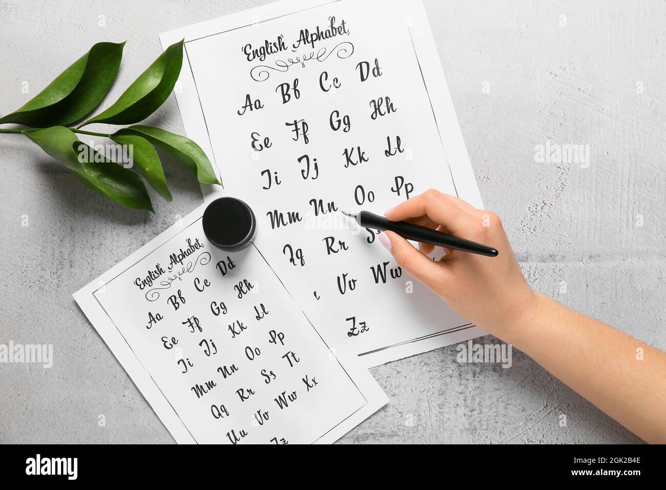 Woman writing English alphabet on light background Stock Photo - Alamy