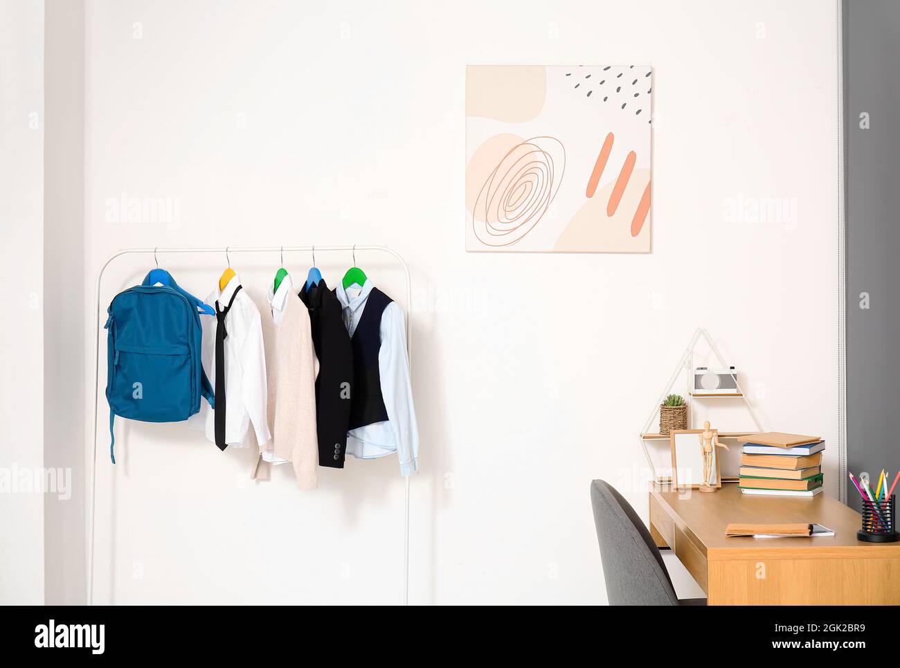 Rack with stylish school uniform and backpack in interior of room Stock ...
