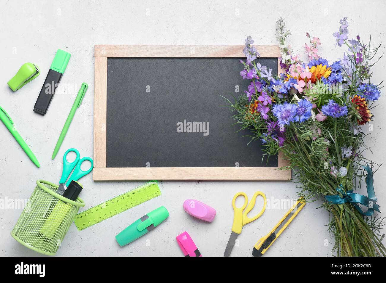 Blank chalkboard, flowers and stationery on light background. Teacher's ...