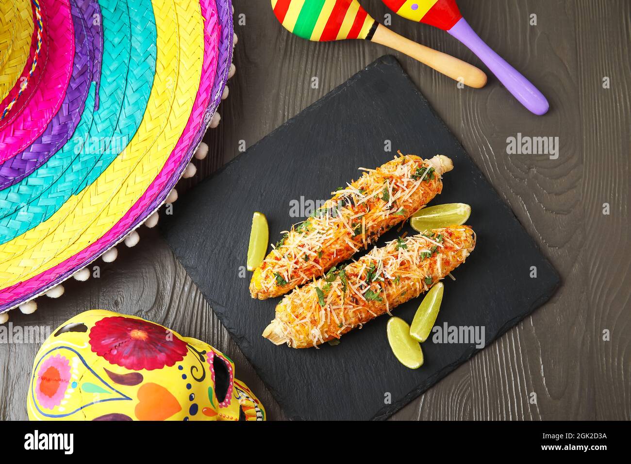 Board with tasty Elote Mexican Street Corn, sombrero and maracas on ...