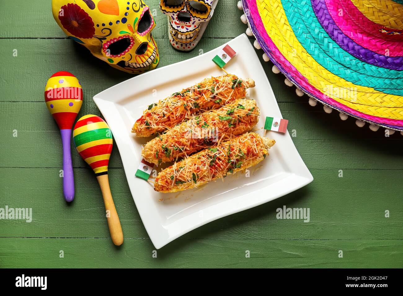 Plate with tasty Elote Mexican Street Corn, painted skull, maracas and ...