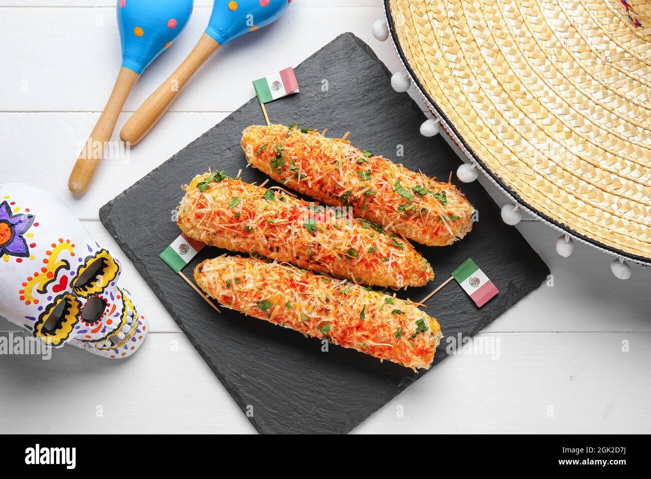 Board with tasty Elote Mexican Street Corn, painted skull, sombrero and ...