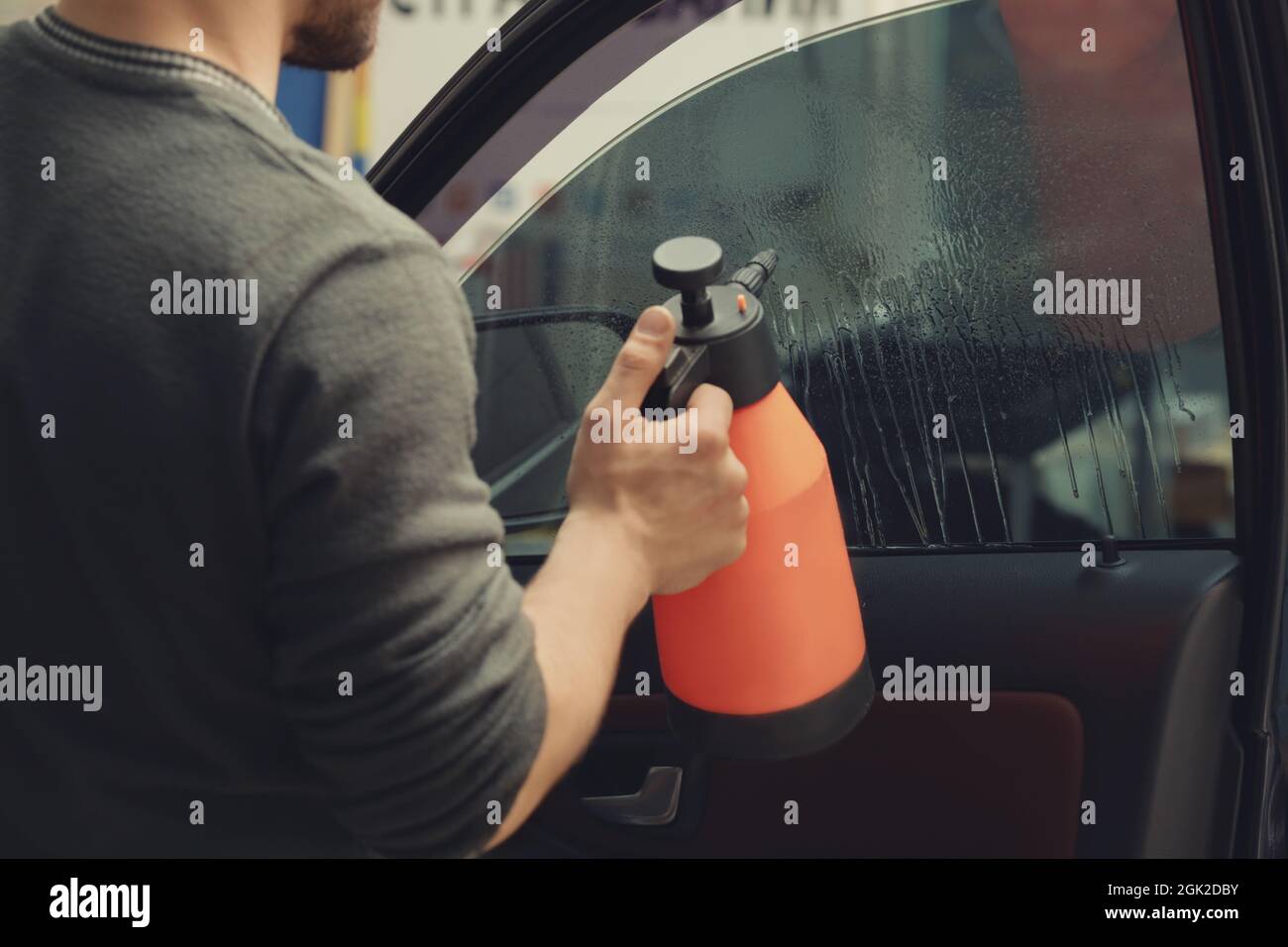 Worker spraying water onto car window Stock Photo - Alamy