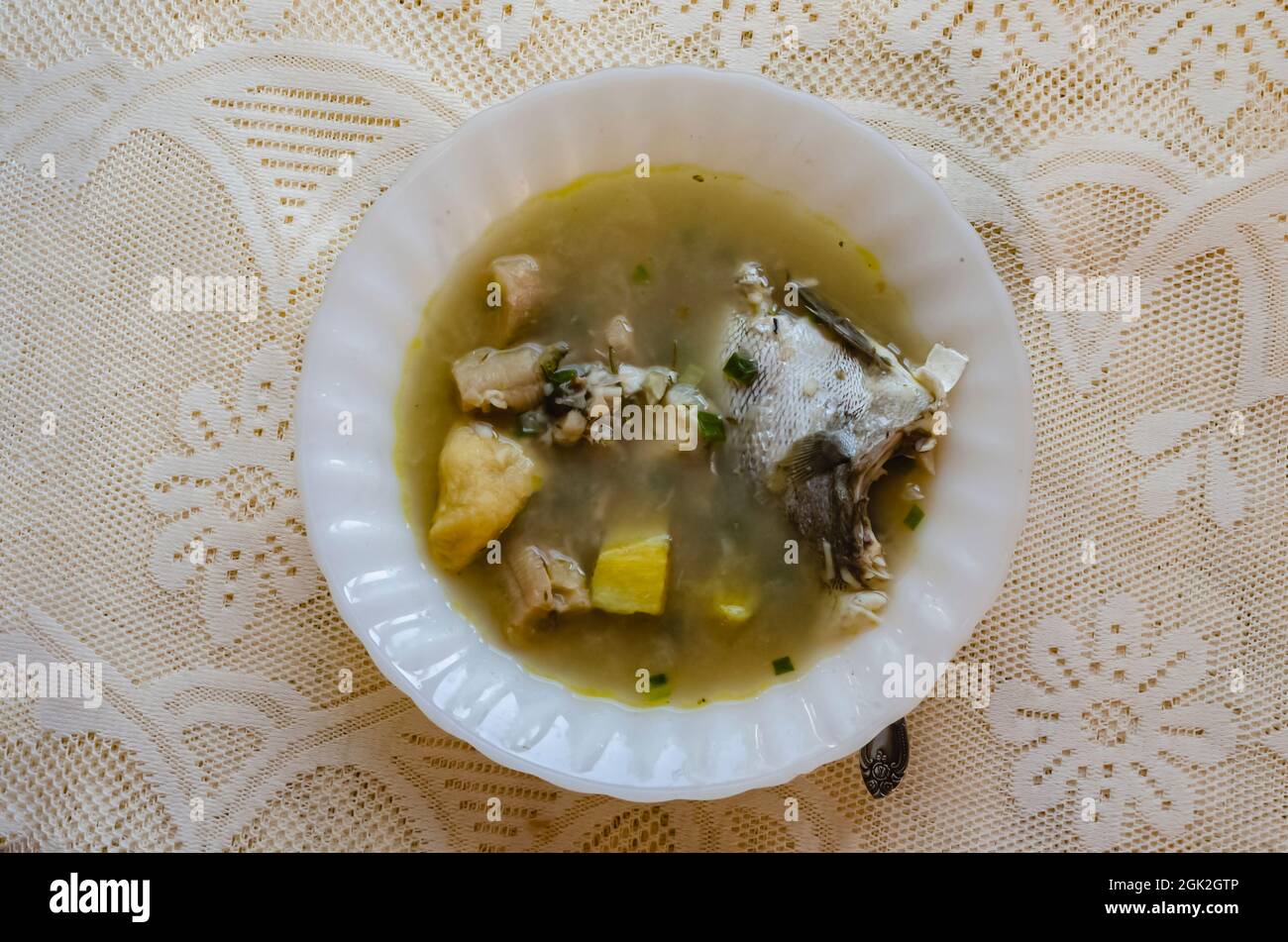 A white soup dish is filled with hot fish soup, fish, banana, sweet ...