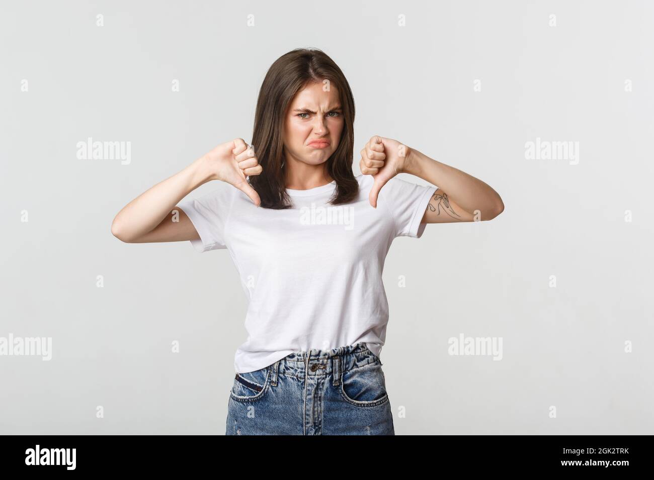 Disappointed grimacing cute girl showing thumbs-down, express dislike ...