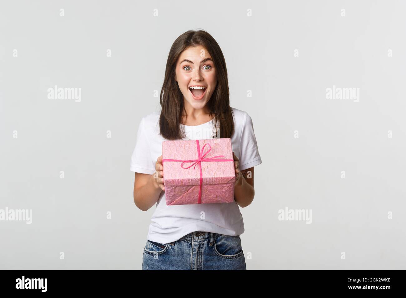 Surprised happy birthday girl receiving wrapped gift, white background ...