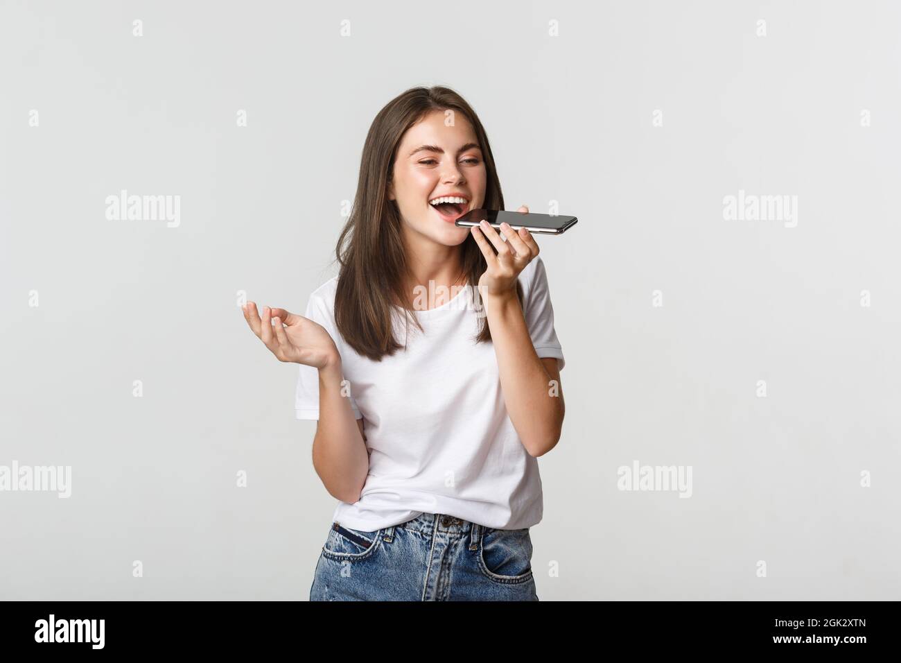 Friendly attractive brunette girl talking on speaker, record voice ...