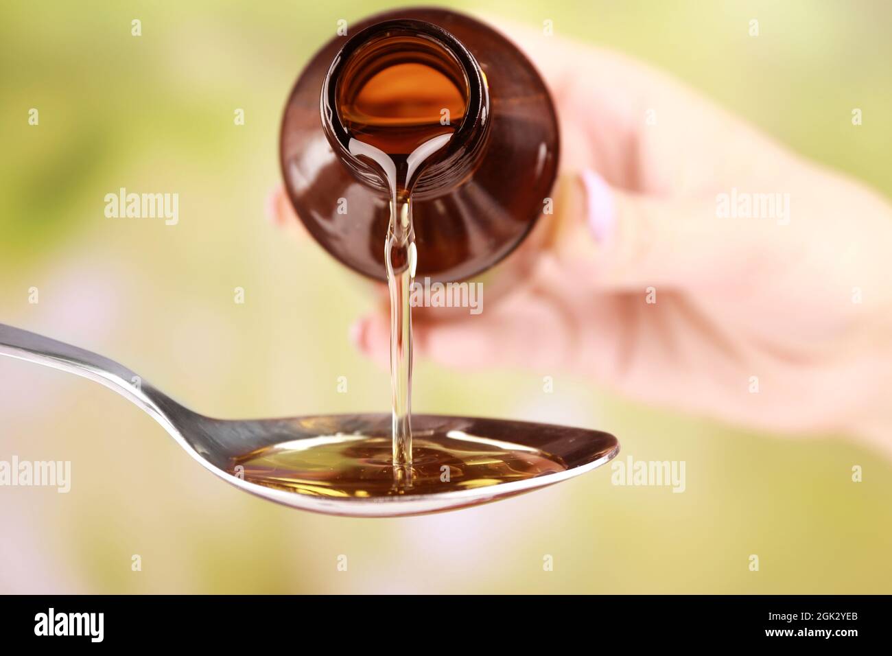 Pouring cough syrup into spoon on blurred background Stock Photo - Alamy