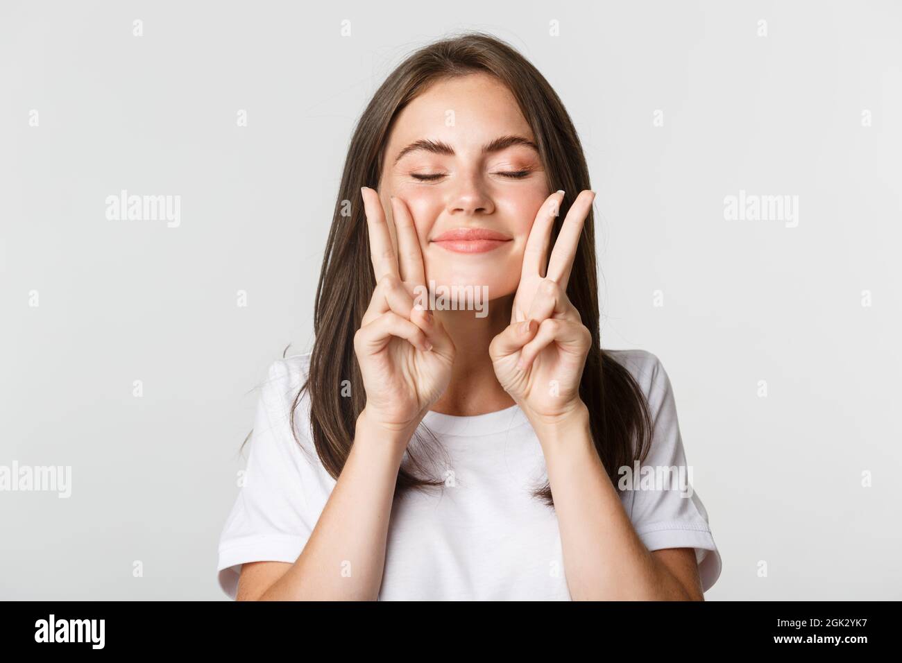 Close-up of happy smiling brunette girl close eyes and showing peace ...