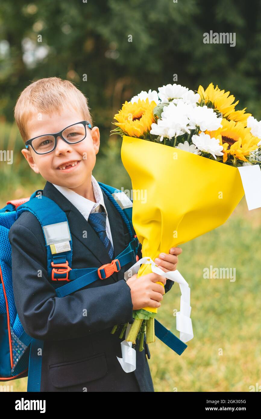 Small smiling boy with flowers ready to go in first class in school. a ...