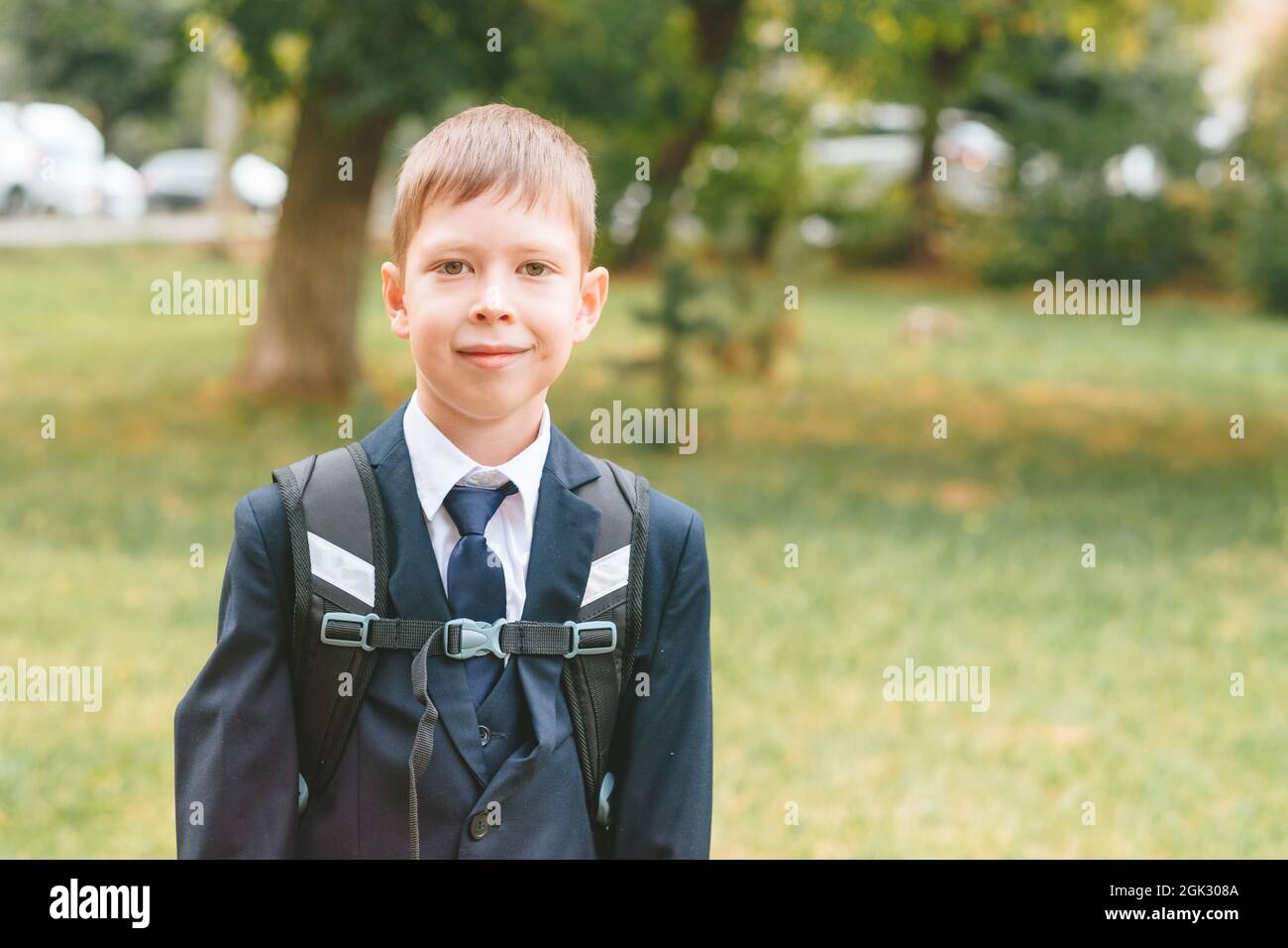a schoolboy in a school uniform and a backpack stands on the street ...