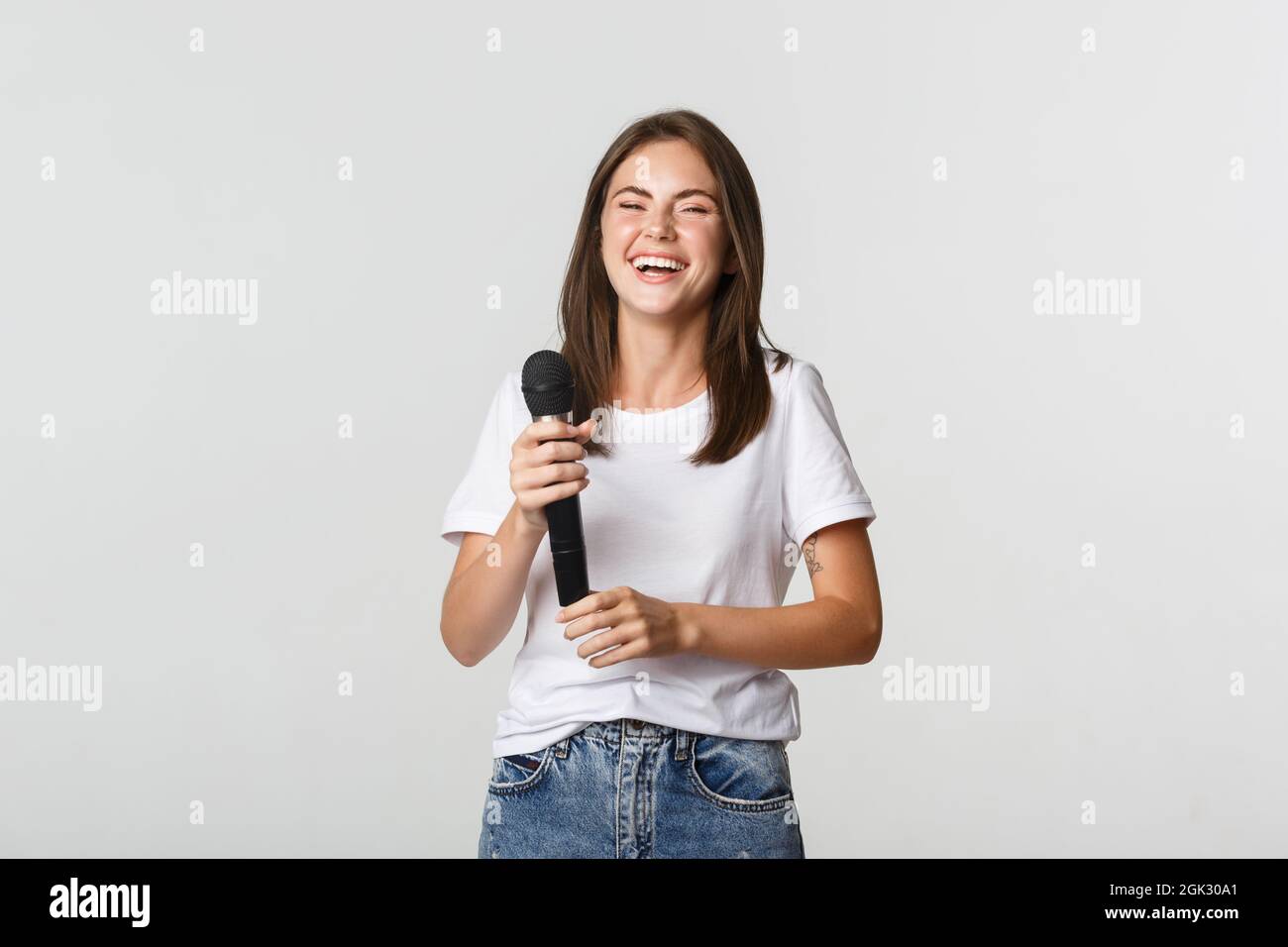 Happy laughing girl holding microphone and singing karaoke, white ...