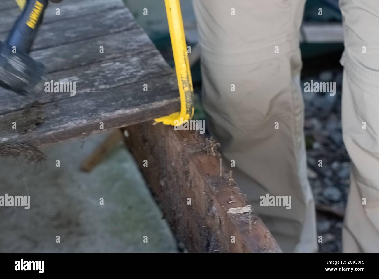 crowbar and mallet deconstructing old weathered deck covered in spider ...