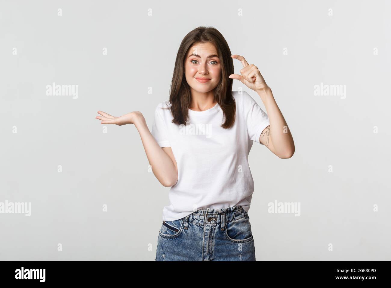 Skeptical and unamused brunette girl showing something too small, tiny ...