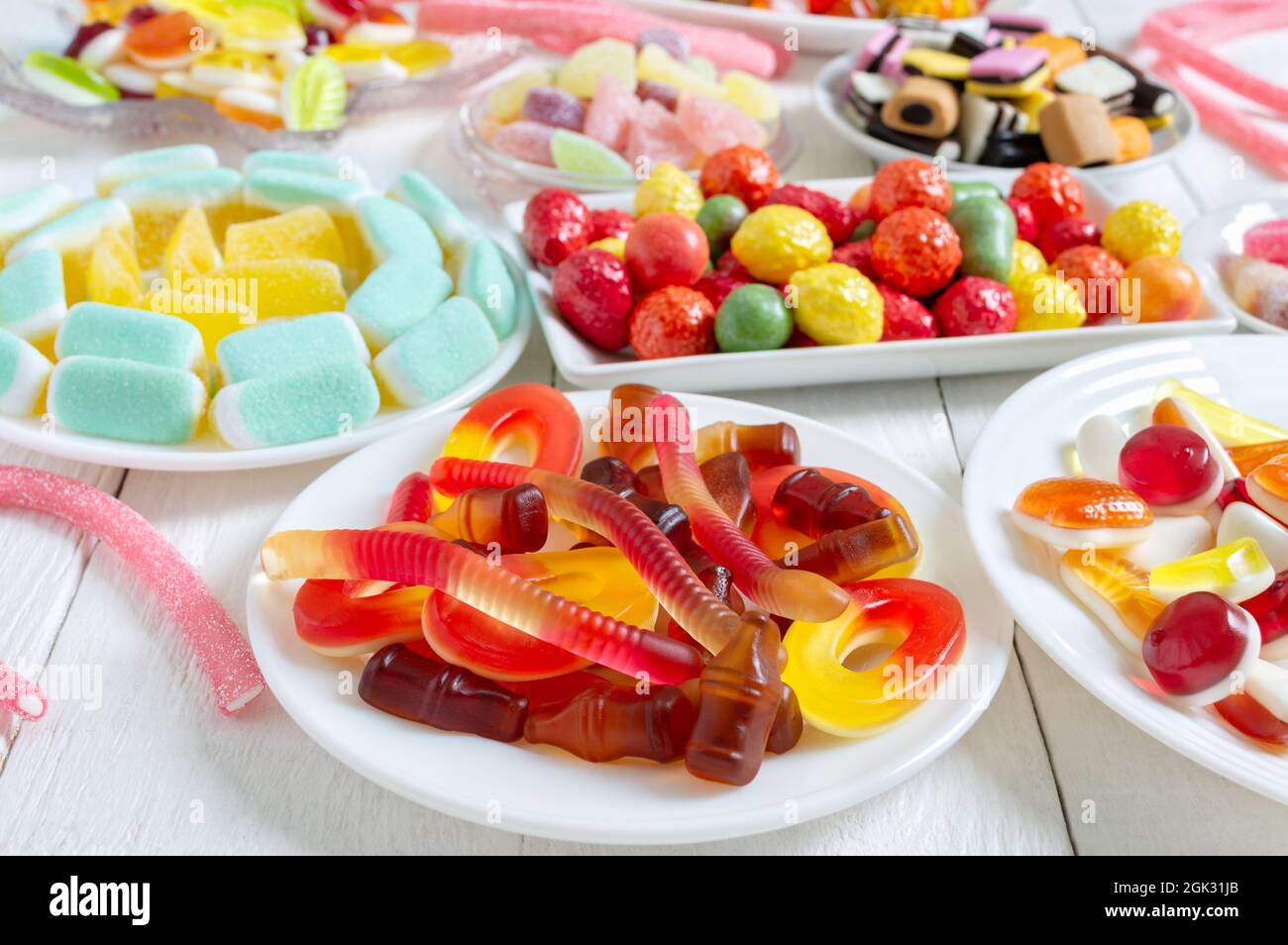 Different delicious colorful gummy candies on plates. Vertical view ...
